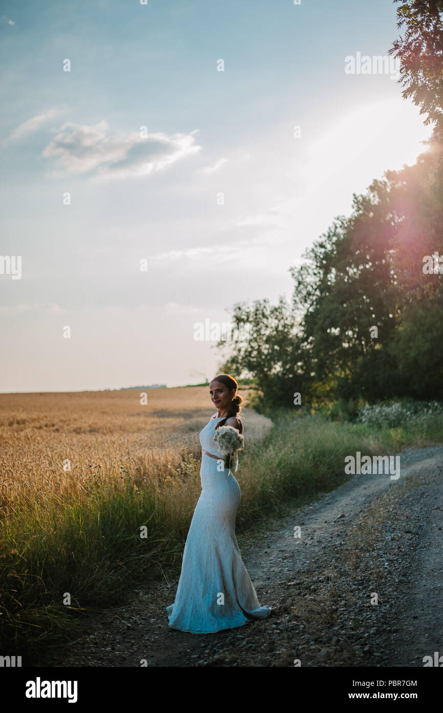 Bride shooting with a bouquet in a field Stock Photo - Alamy