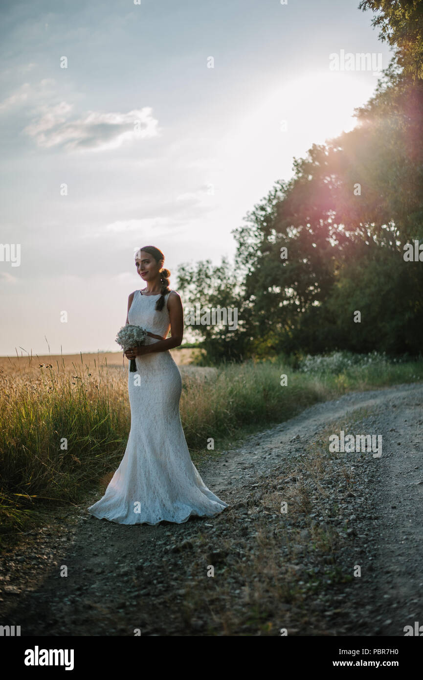 Bride shooting with a bouquet in a field Stock Photo - Alamy