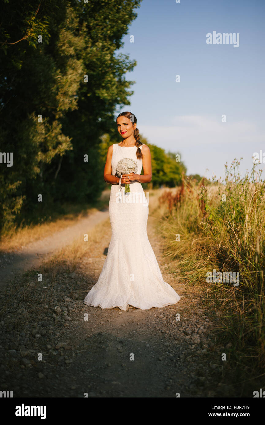 Bride shooting with a bouquet in a field Stock Photo - Alamy