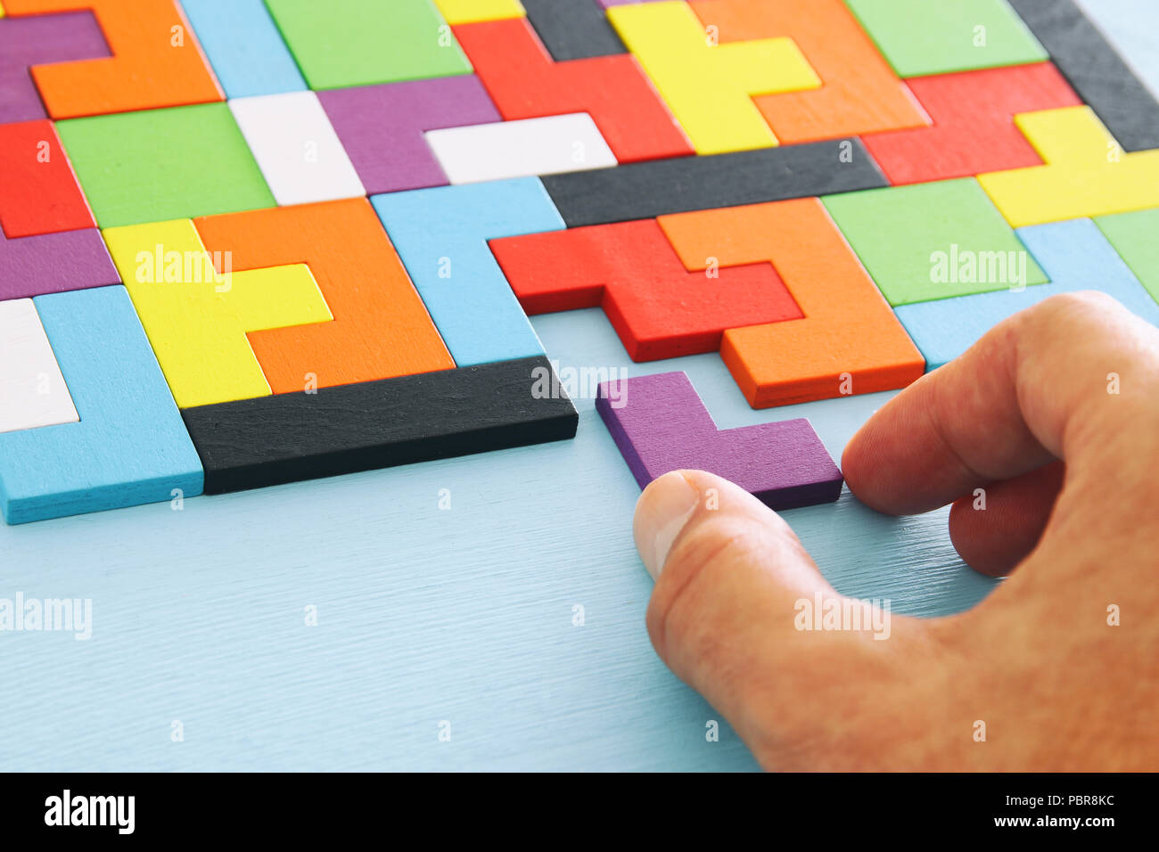 man's hand holding a square tangram puzzle, over wooden table Stock ...