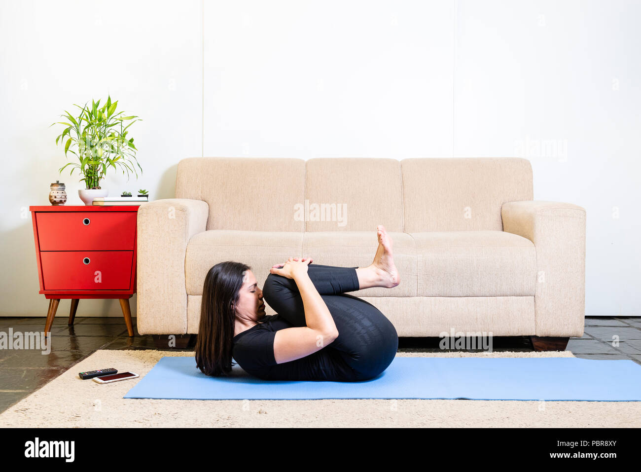 Beautiful caucasian brunette woman in black clothes on blue yogamat ...