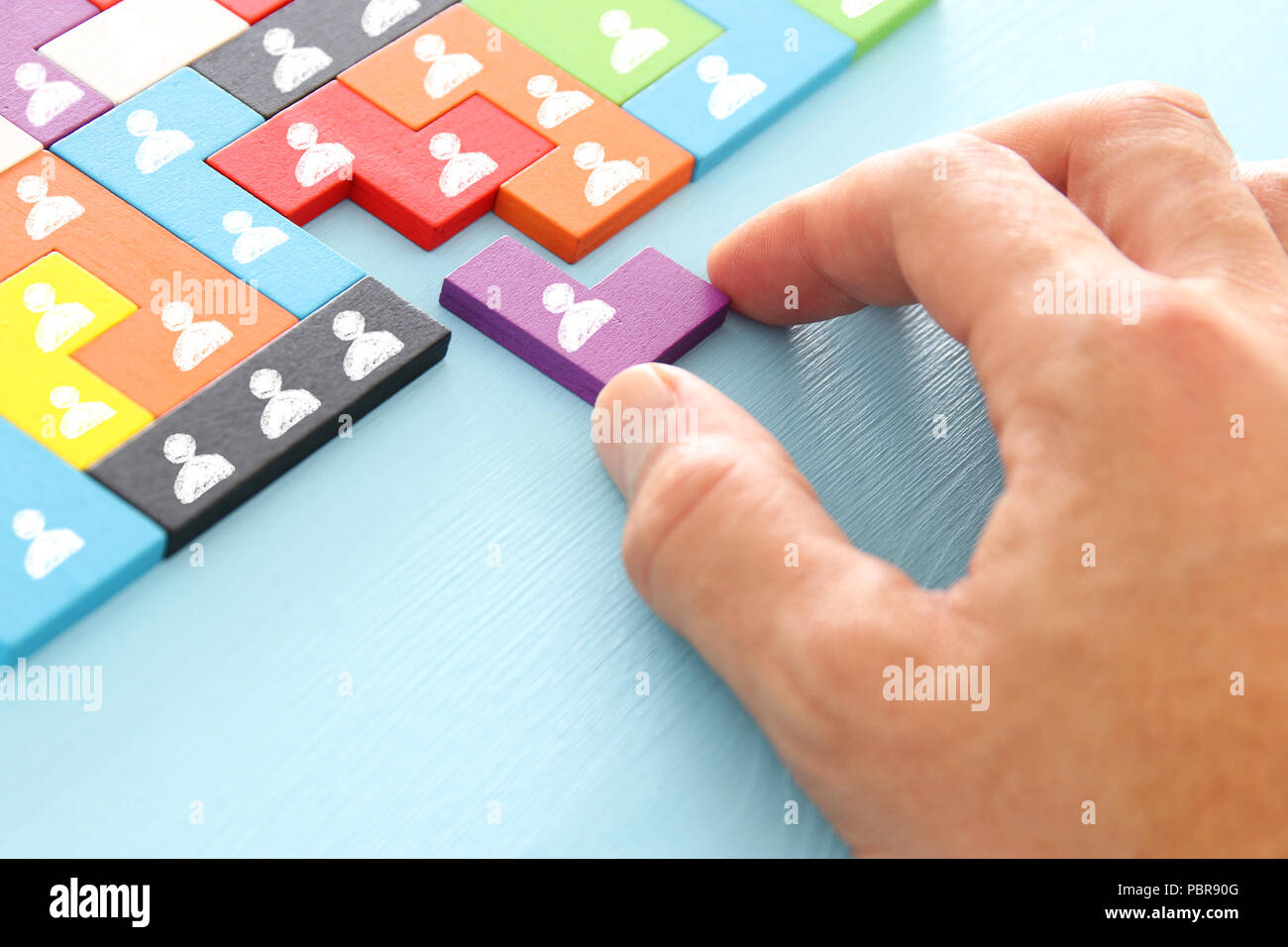 image of tangram puzzle blocks with people icons over wooden table ...
