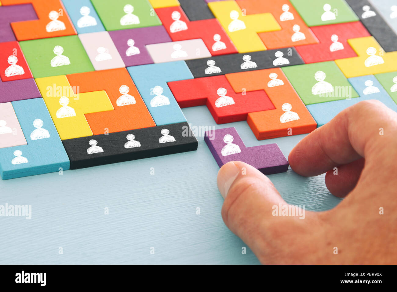 image of tangram puzzle blocks with people icons over wooden table ...
