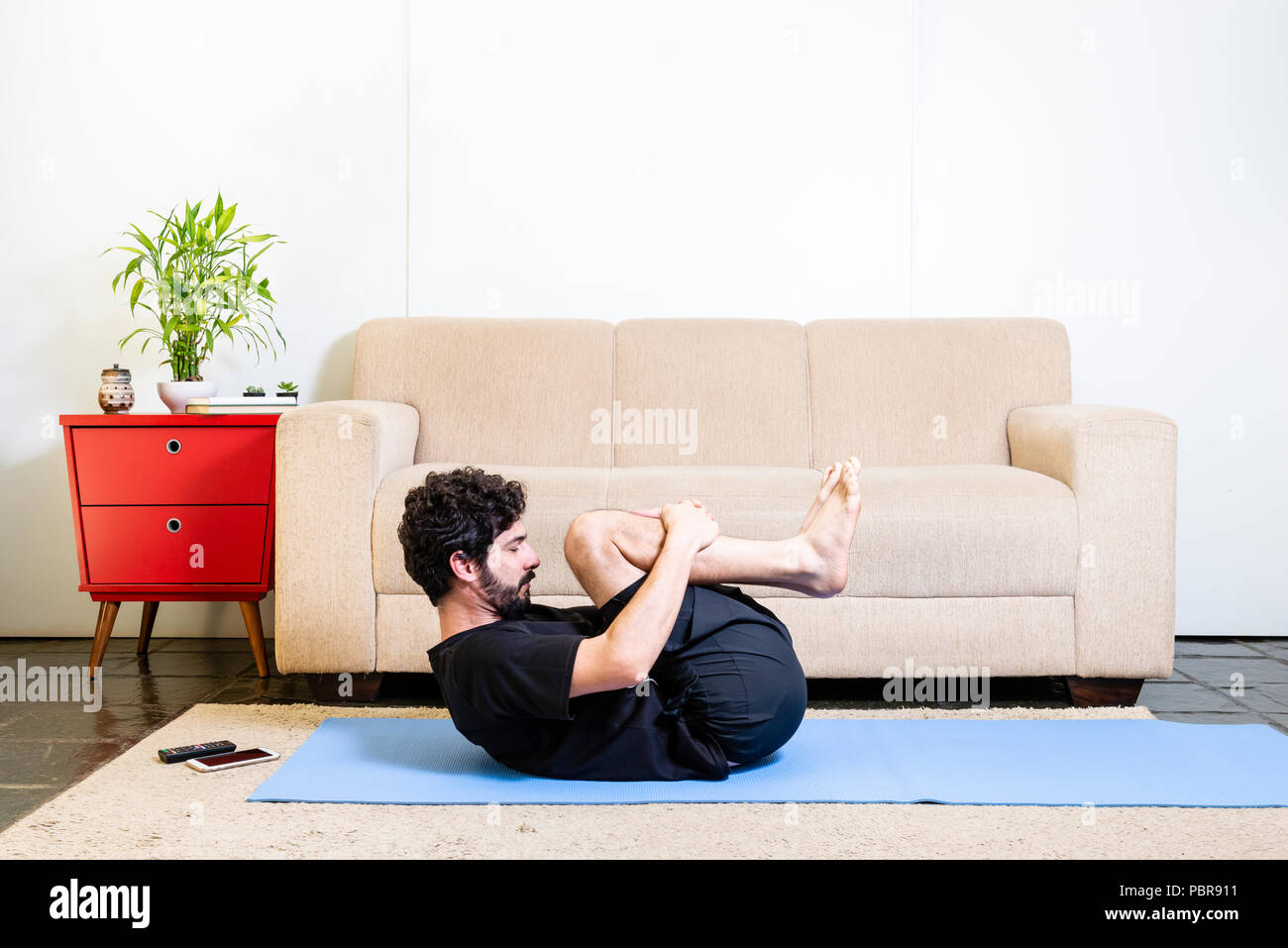 Beautiful caucasian bearded man in black clothes on blue yogamat doing ...