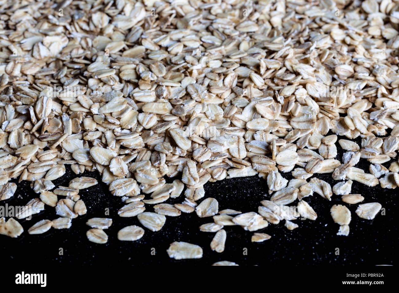 Oatmeal rolled oats grains spread on black surface from side Stock ...