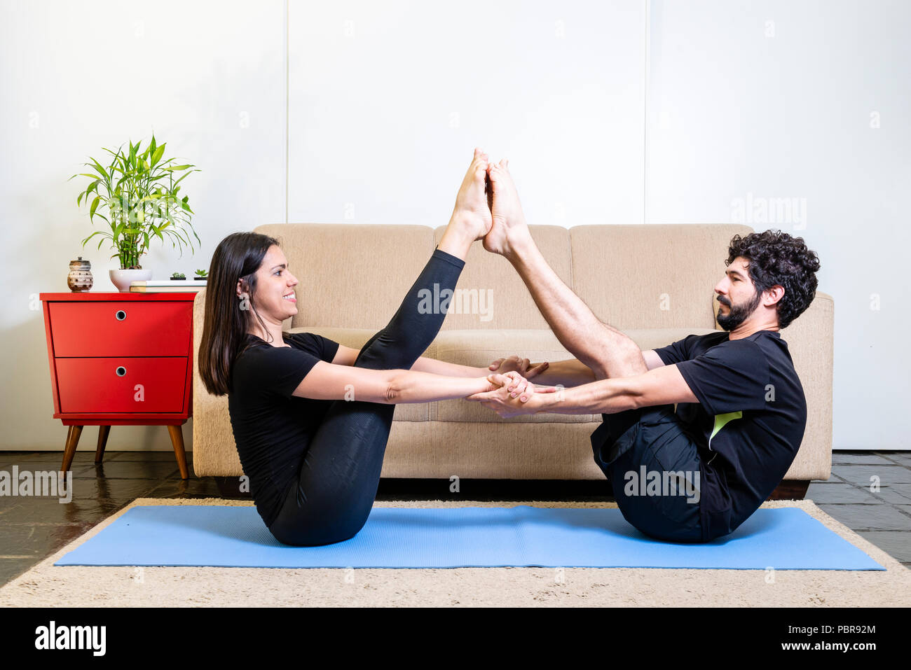 Beautiful hetero caucasian couple in black clothes on blue yogamat ...