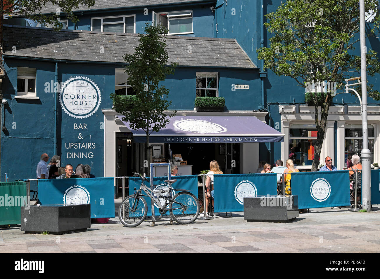 Exterior view of people eating at tables outside The Corner House bar ...