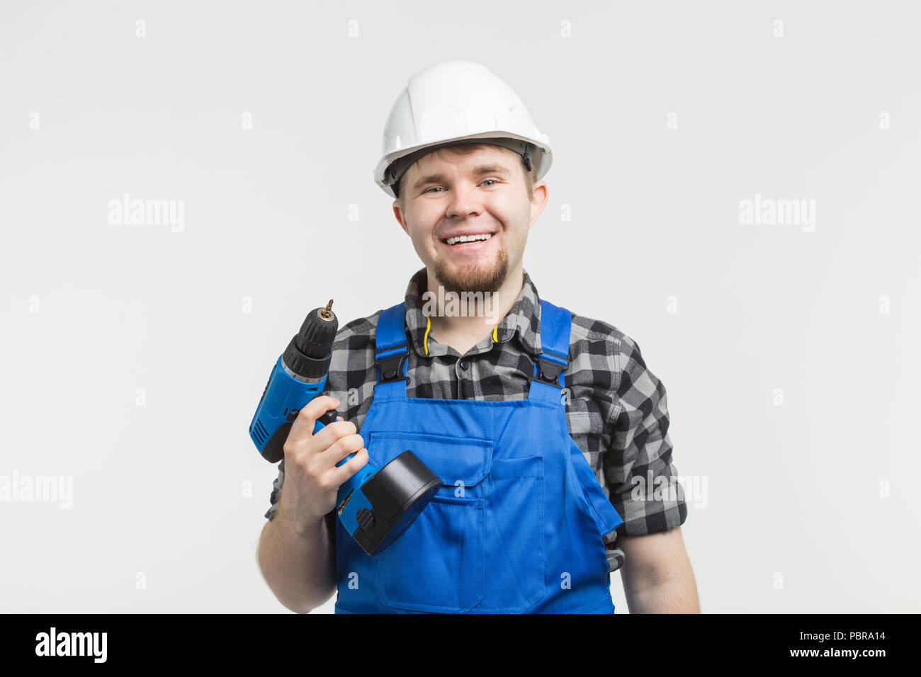 Close-up of handsome male builder with screwdriver wearing white helmet ...