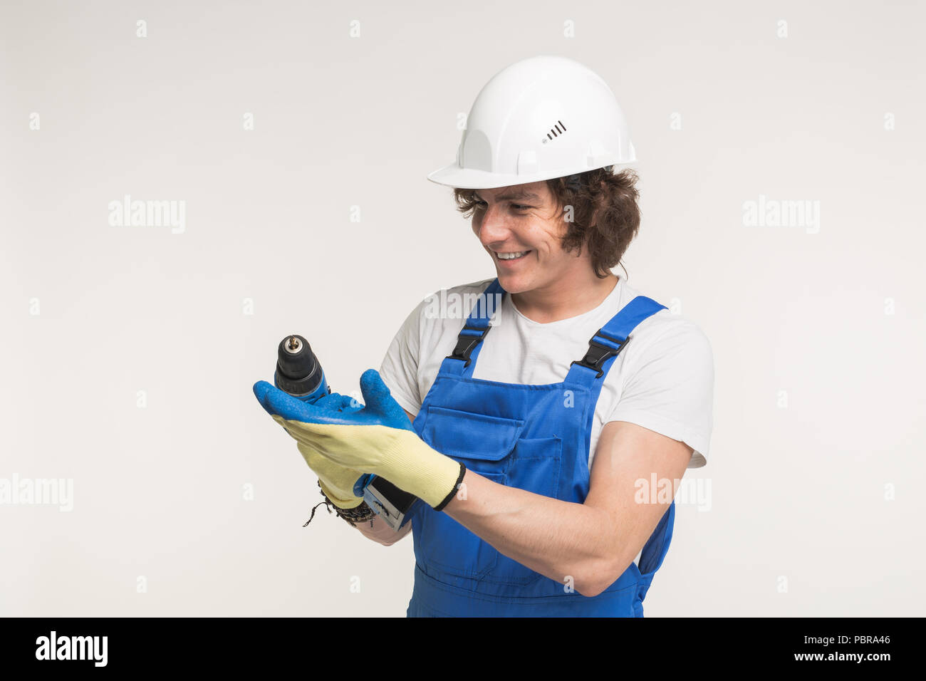 Portrait of handsome happy builder with skrewdriver on white background ...