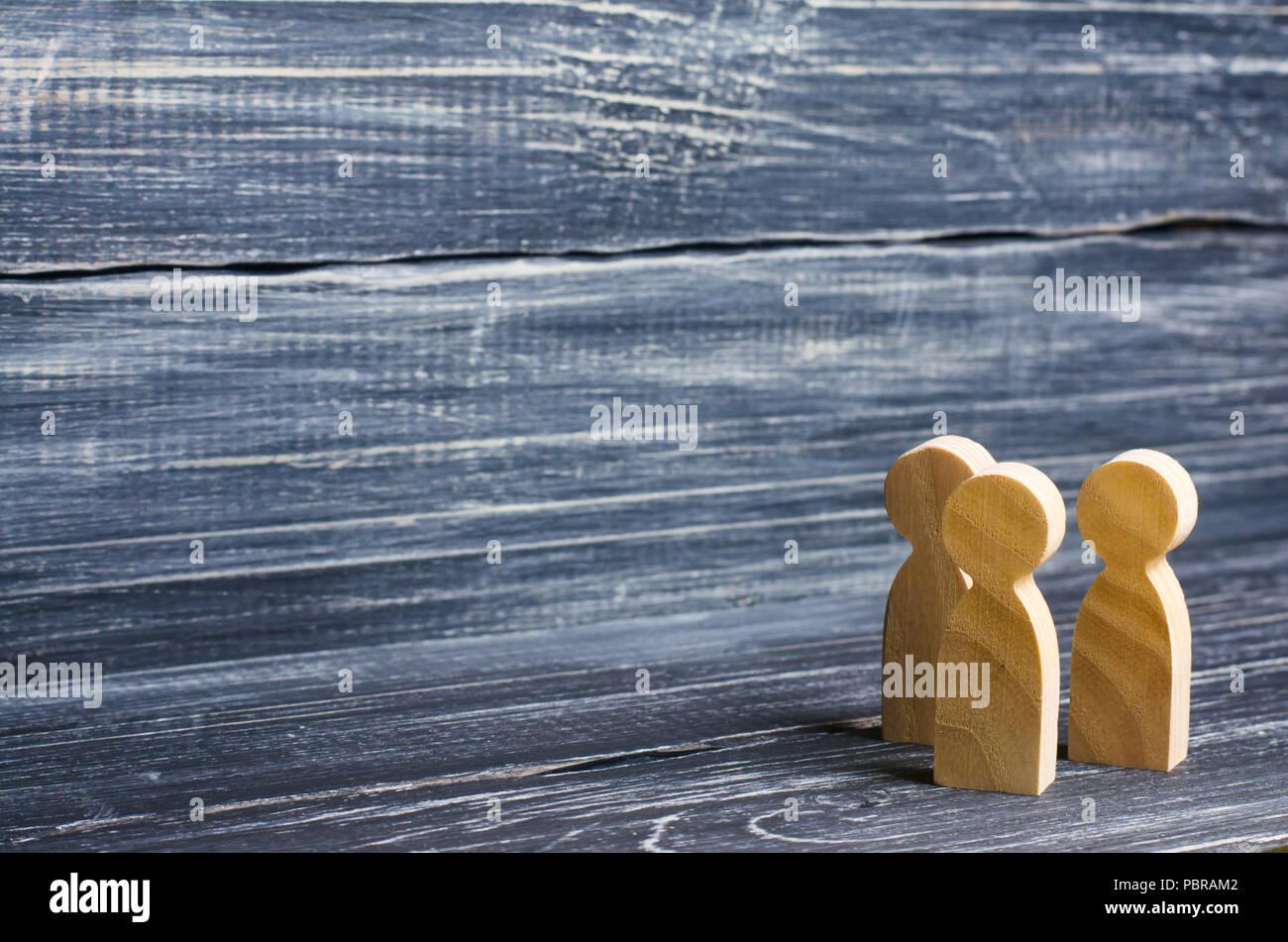 Three wooden human figures stand together. Social concept, family, team ...