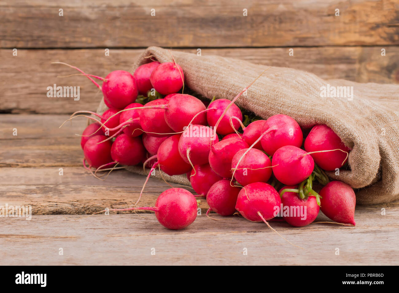 Radishes harvest in a sack. Wooden desk background Stock Photo - Alamy