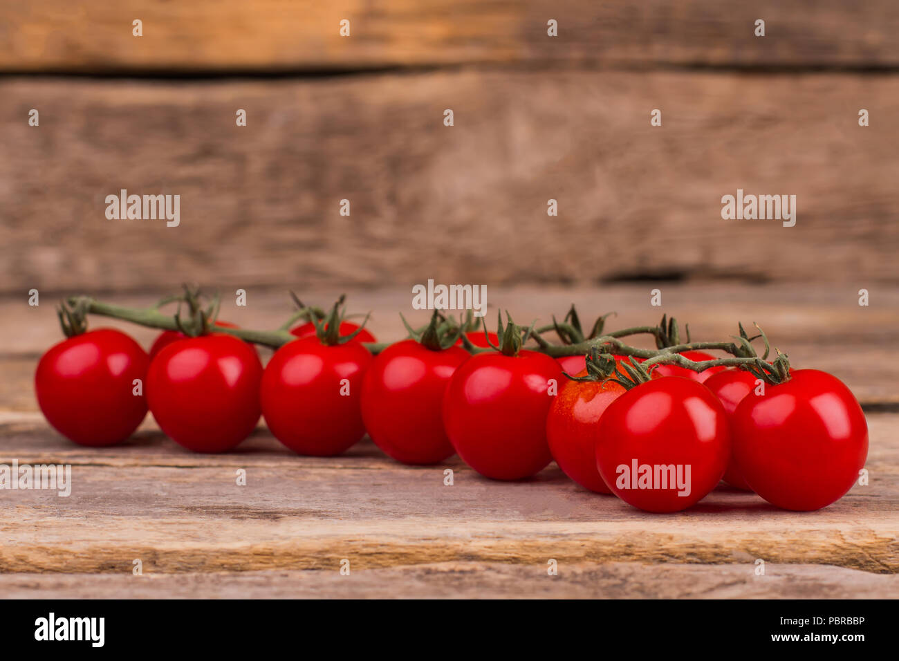 Stem of red shiny tomatoes. Old rustic wooden desk surface Stock Photo ...