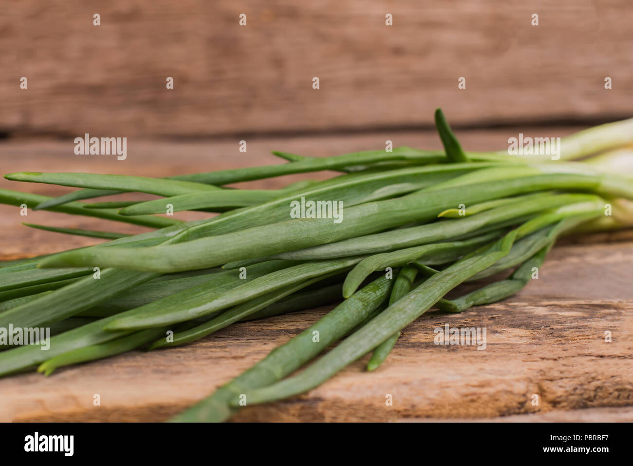 Green onion on the table close up. Wooden desk background Stock Photo ...