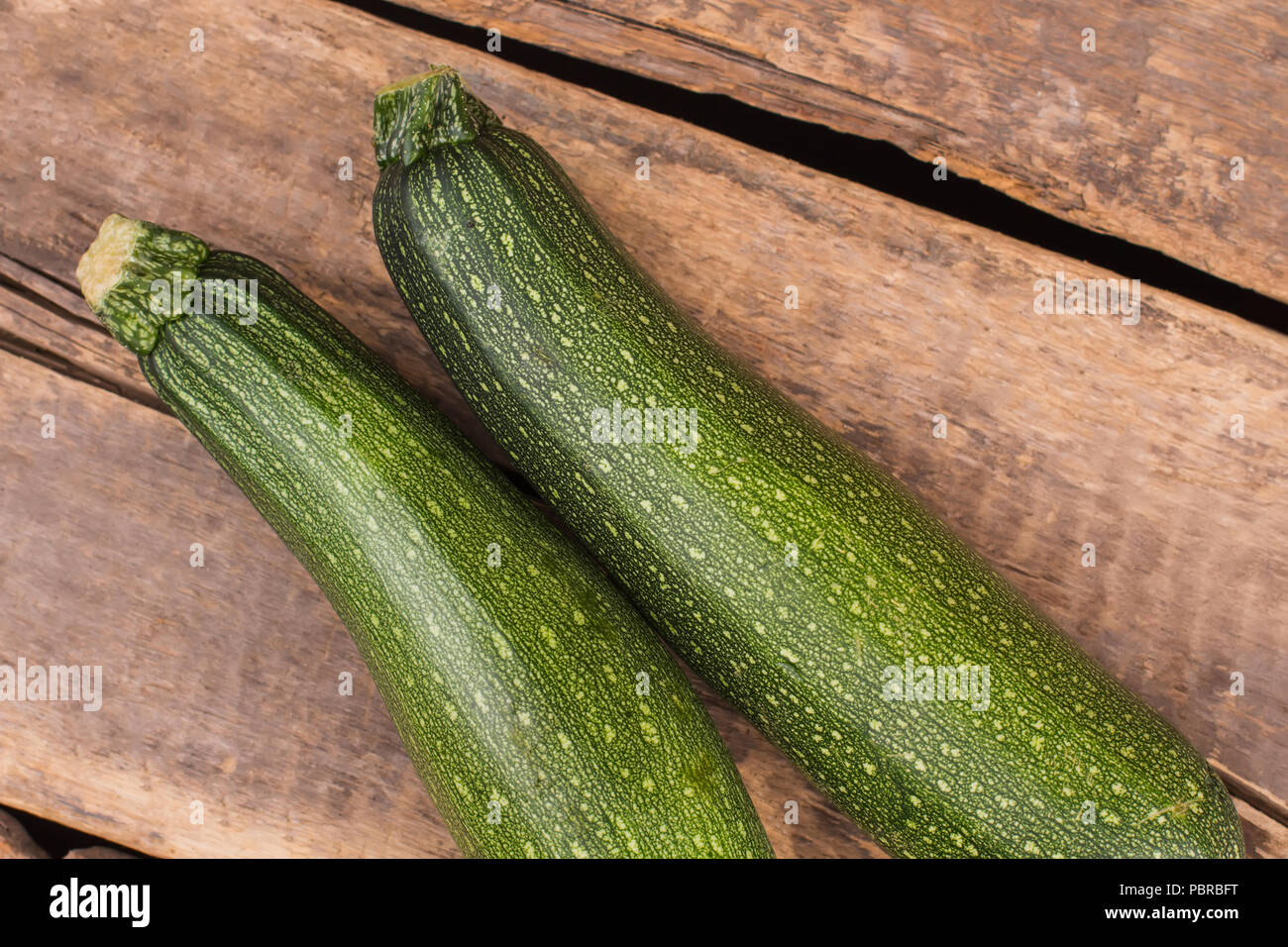 Two zucchini or courgettes on old wooden background. Top view, close up ...