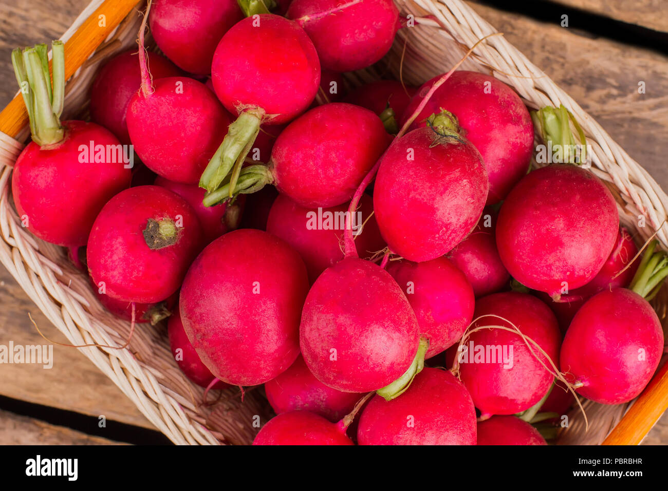 Many radishes in a basket. Top view. Old wooden desk table background ...