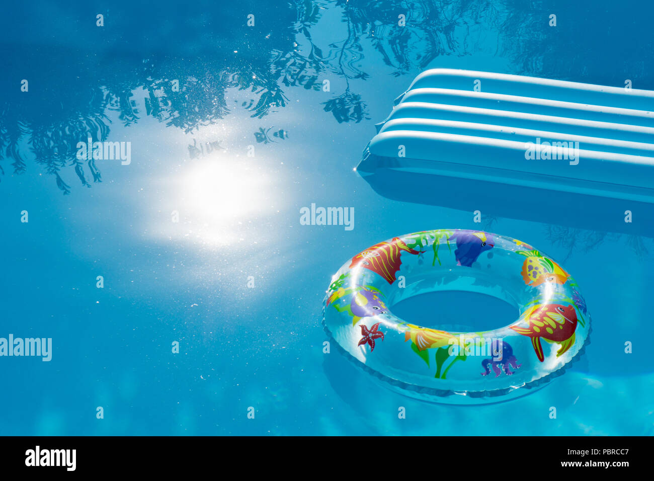 Inflated buoy and mattress floating on water of a swimming pool. Summer ...