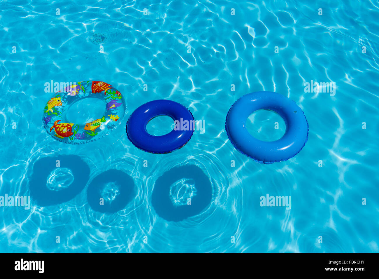 Top view of three inflatable buoys floating over a blue swimming pool ...