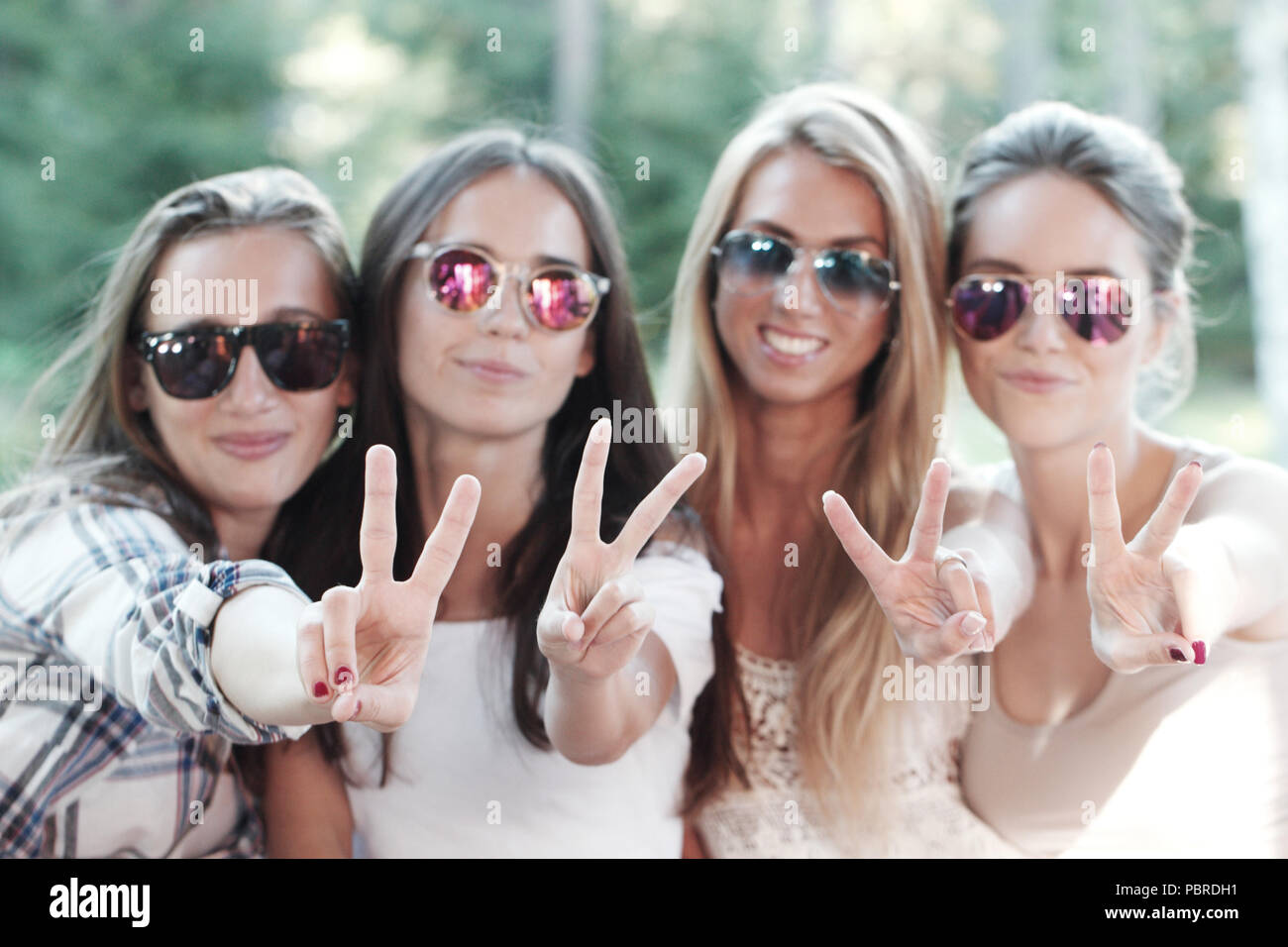 Happy smiling girlfriends showing a v hand sign Stock Photo - Alamy