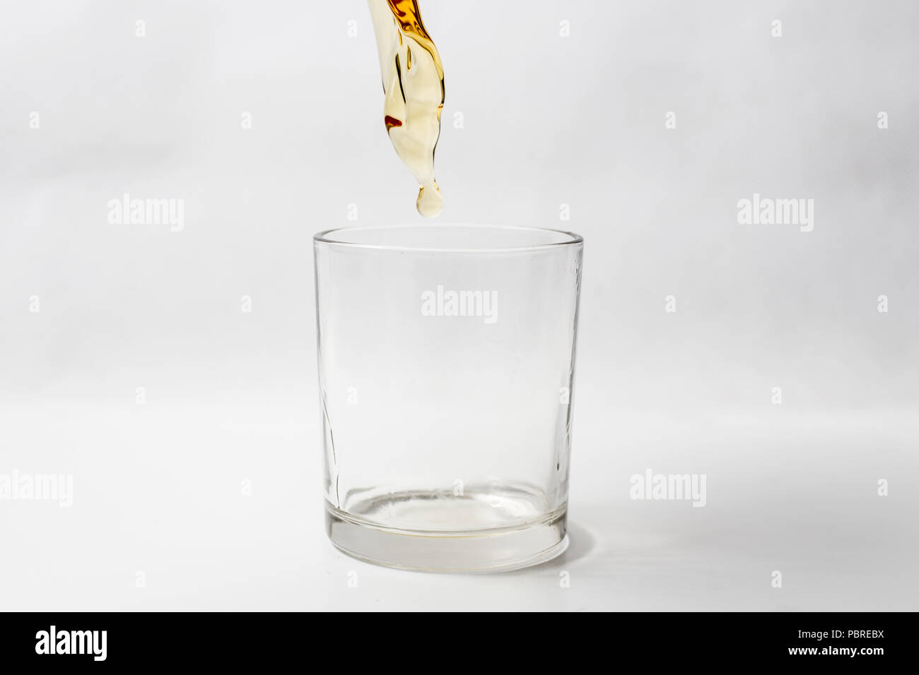 Whiskey pouring in empty glass on white background Stock Photo - Alamy