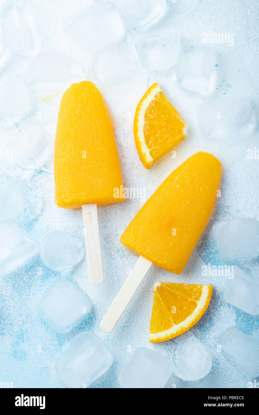 Orange popsicles with juice on a blue background. Ice pops, flat lay ...