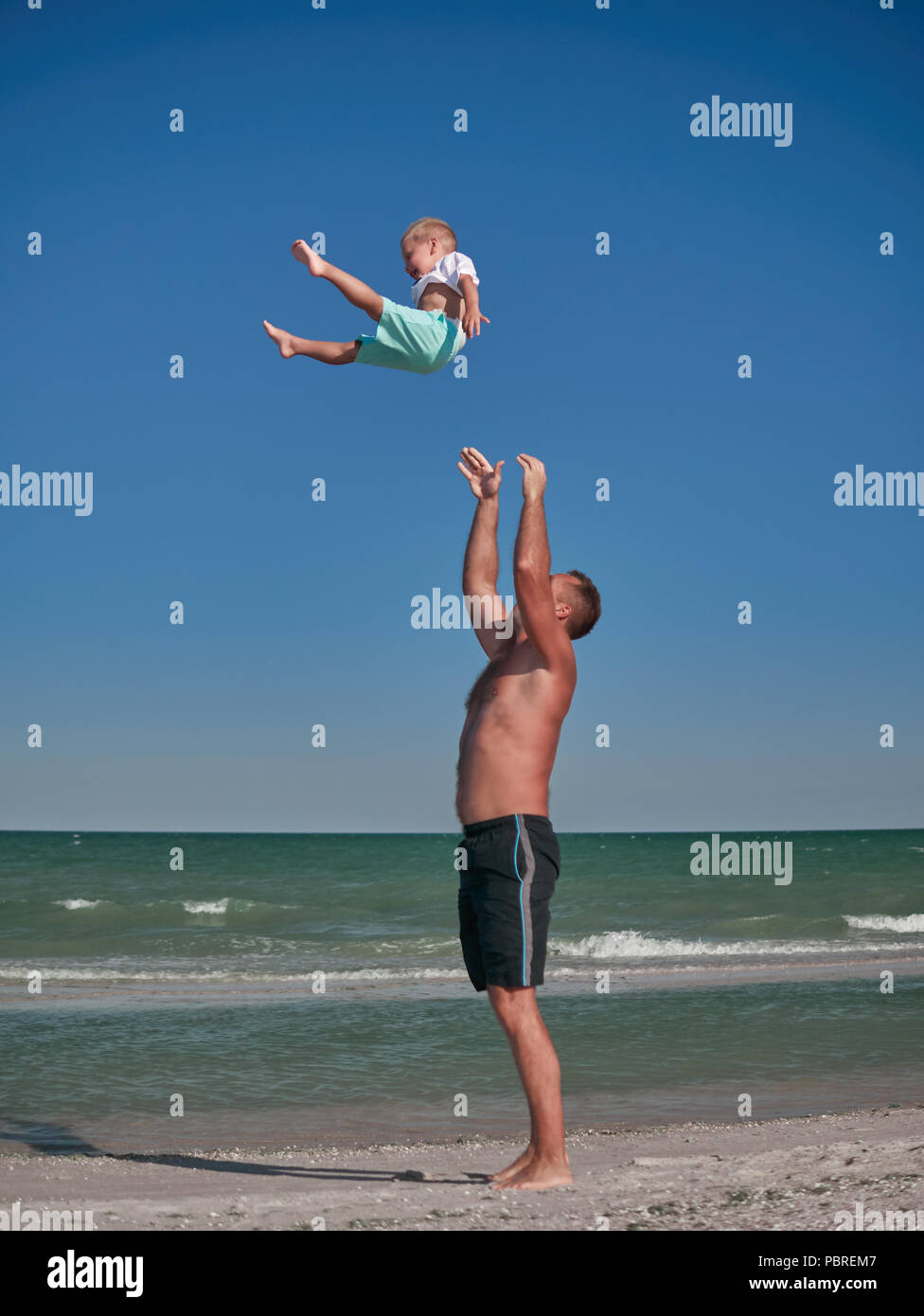 Dad and Baby playing on seaside in summertime. Happy family and happy ...