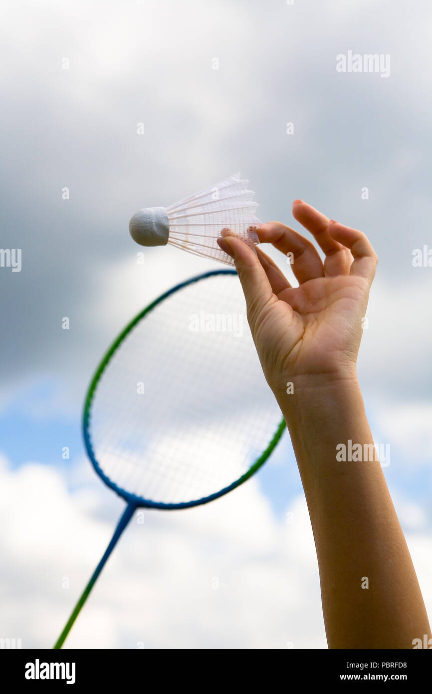 Elegant fingers of a female hand hold a shuttlecock, in the background ...
