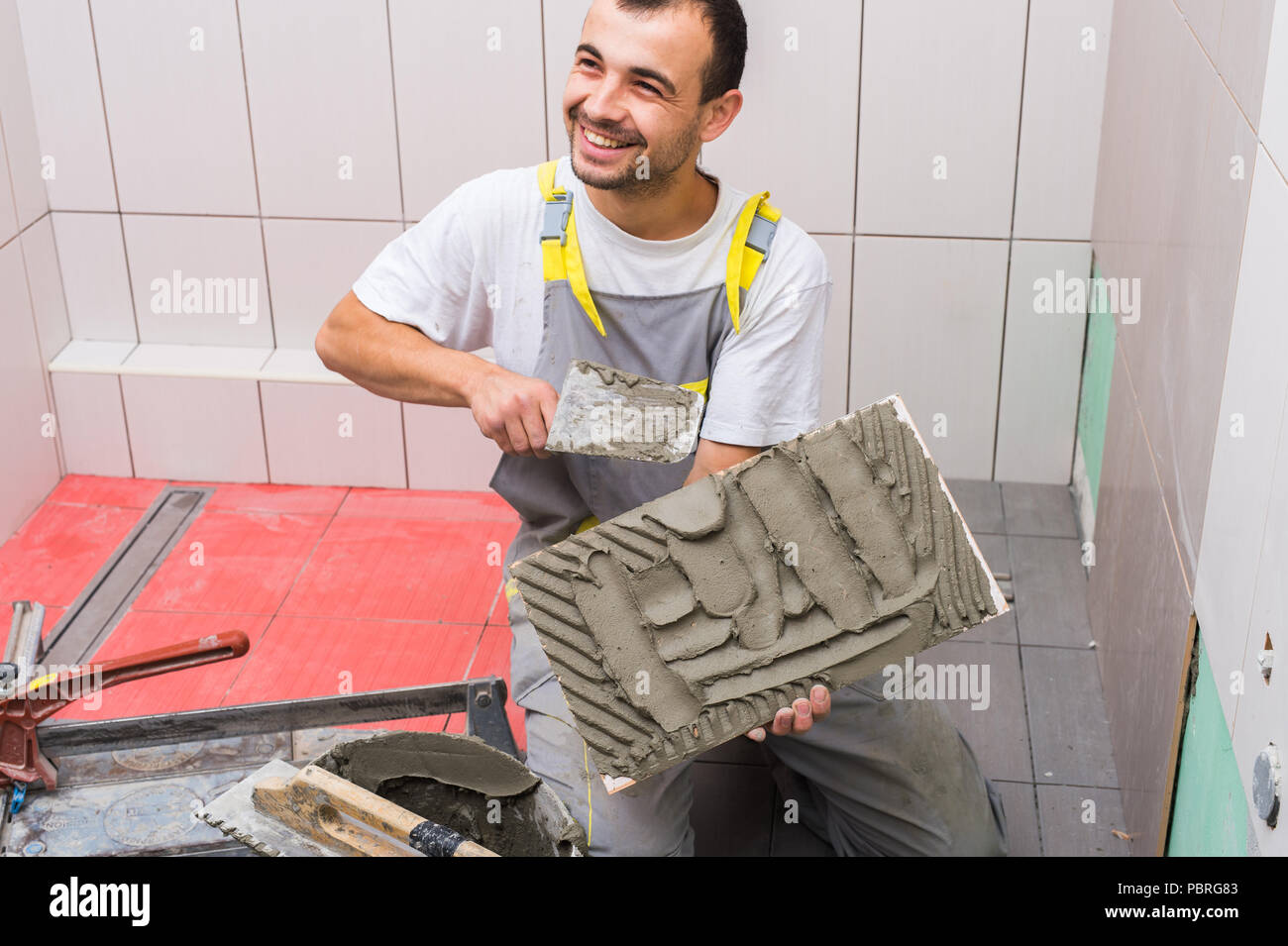industrial tiler builder worker installing floor tile Stock Photo - Alamy