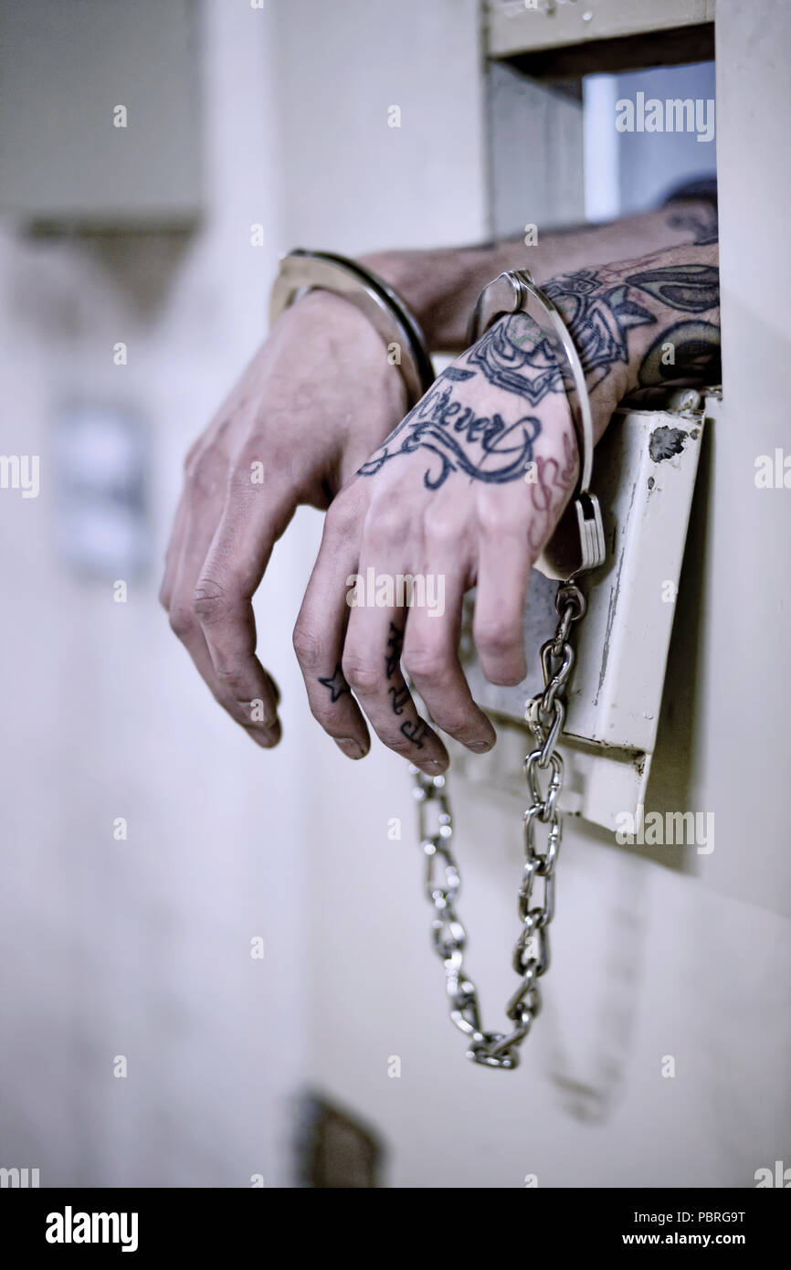 hands of tattoed prisoner locked with handcuff in jail background Stock ...