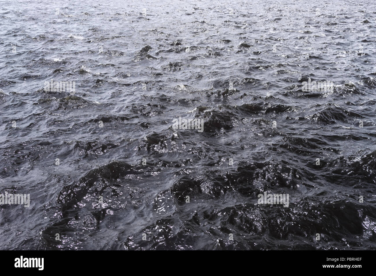 A strong wind drives small waves on the water fall, turning it into a ...