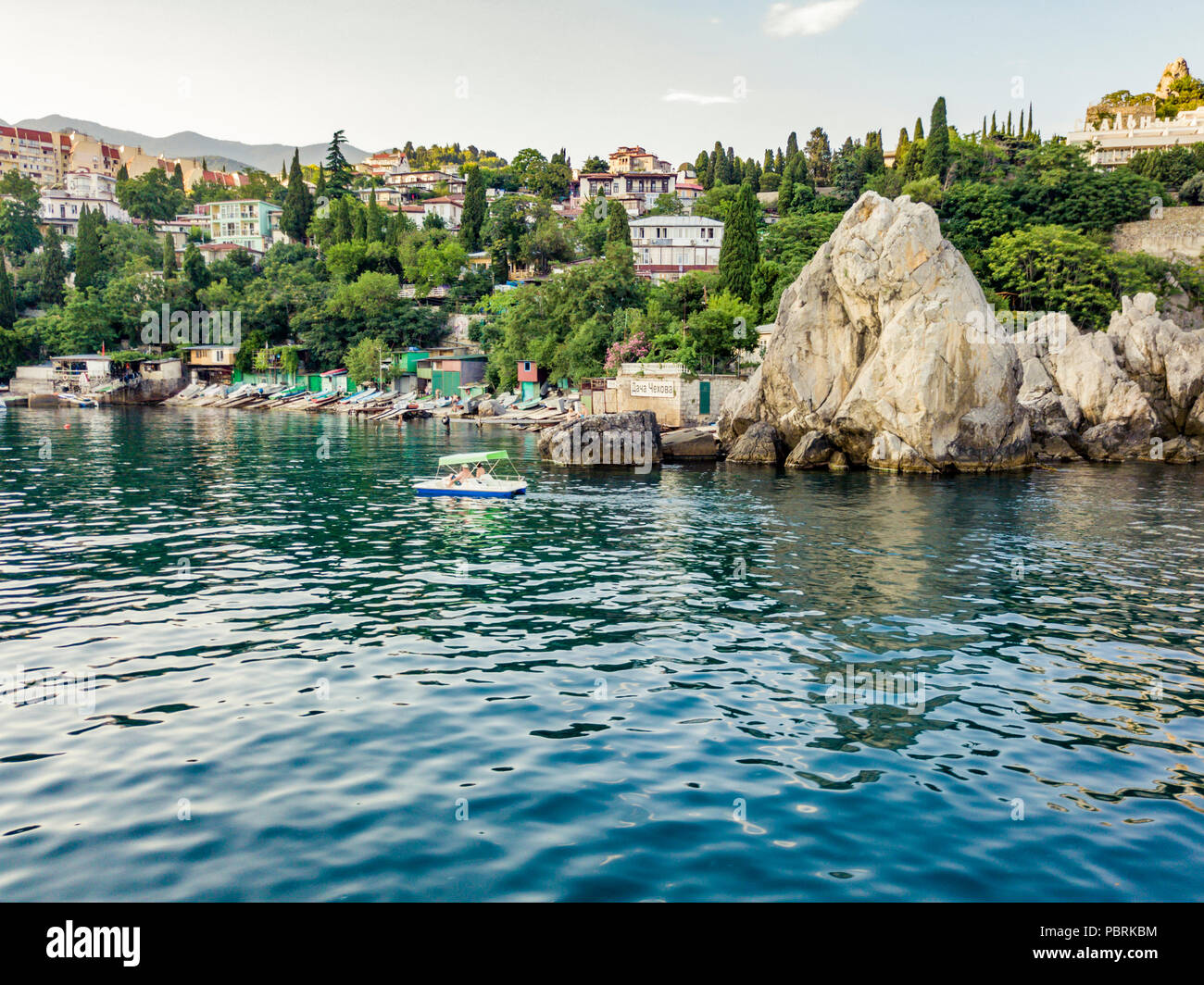 touristic small catamaran passing by the rock cliff coast on the sea ...