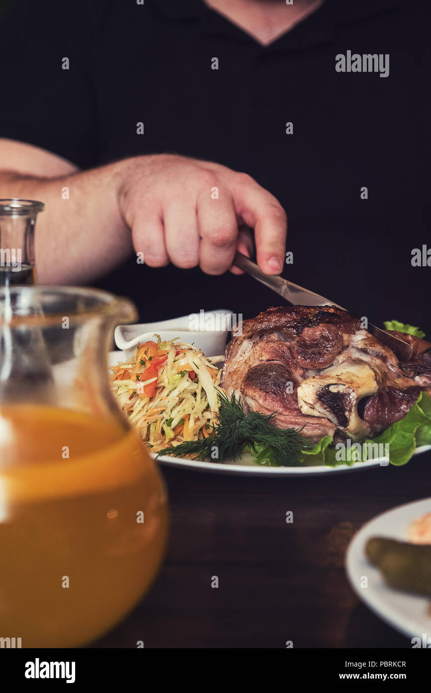 Man eats tasty dish of pork shank Stock Photo - Alamy