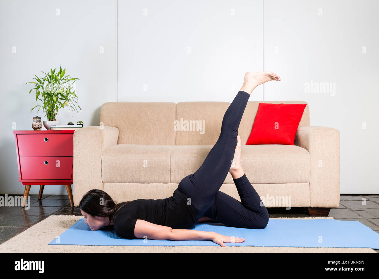 Beautiful caucasian brunette woman in black clothes on blue yogamat ...