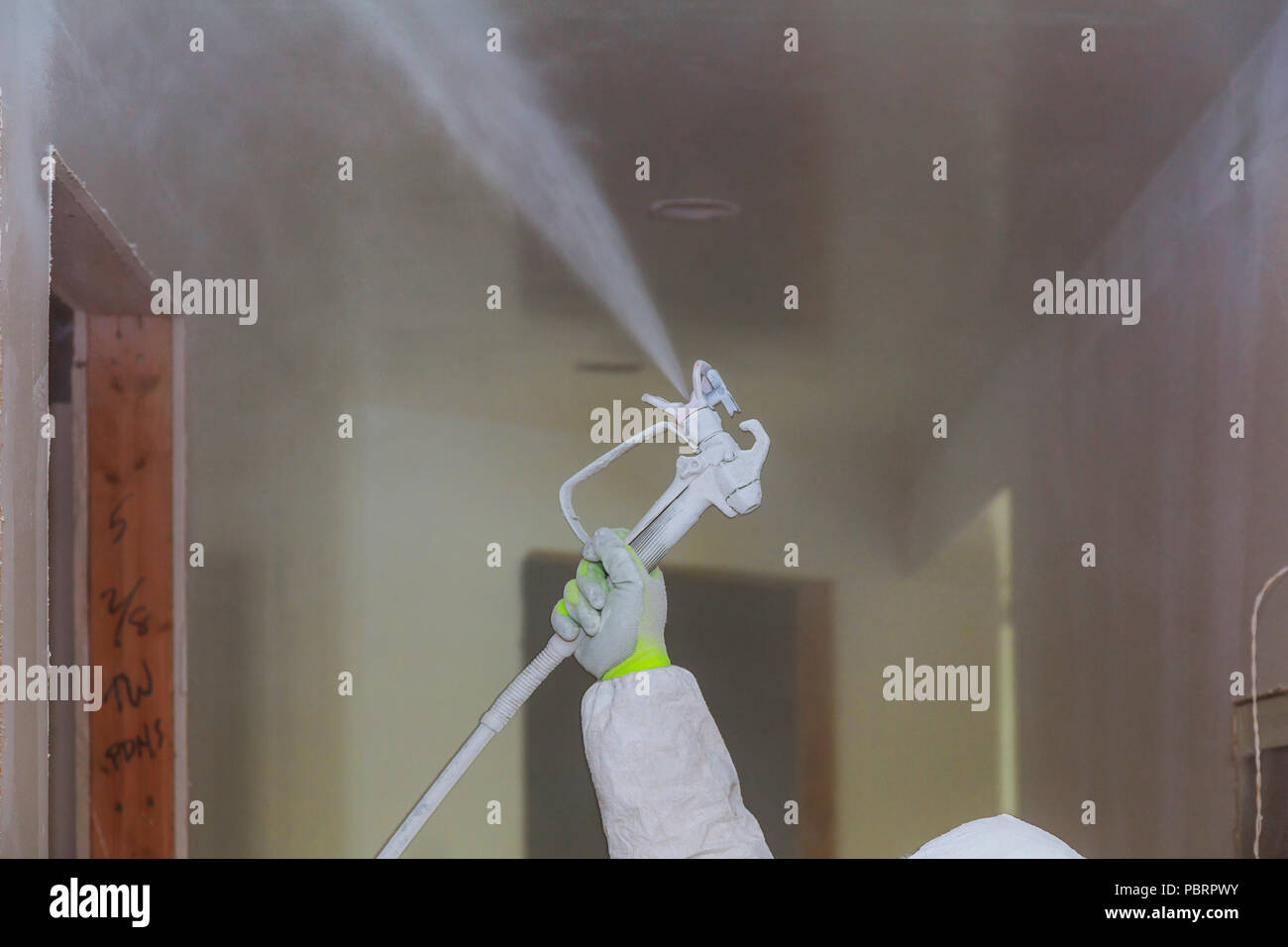 Worker painting wall with spray gun in white color hand the tool the ...