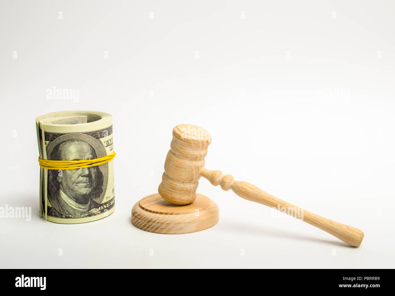A wooden judge hammer and a bundled bundle of dollars on a white ...