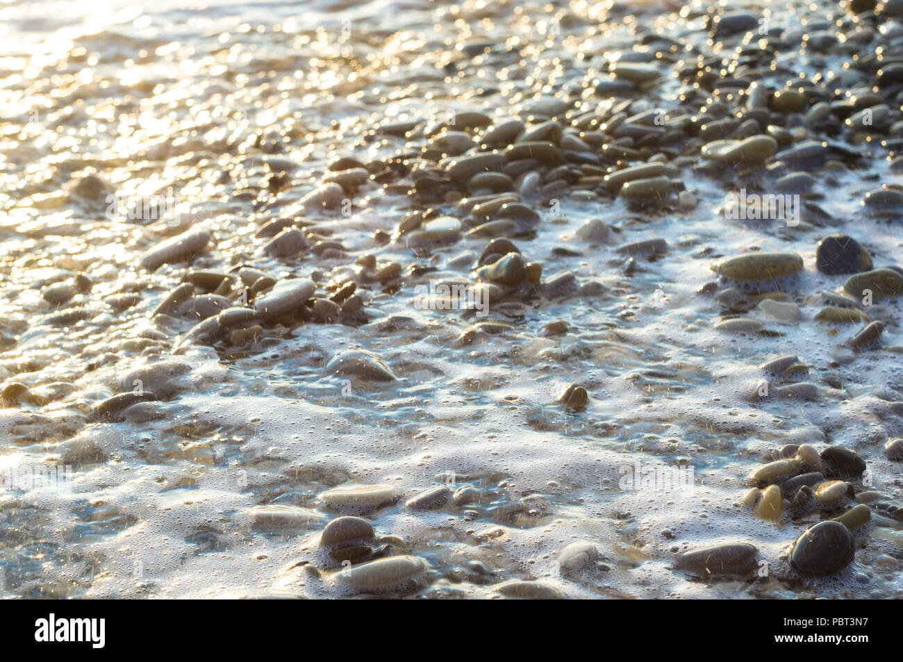 pebble stones on the sea beach, the rolling waves of the sea with foam ...