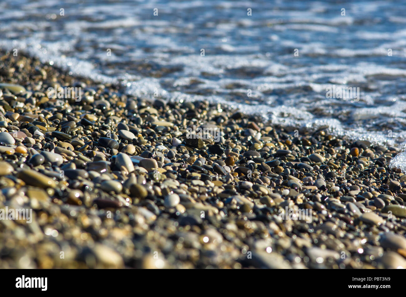 pebble stones on the sea beach, the rolling waves of the sea with foam ...