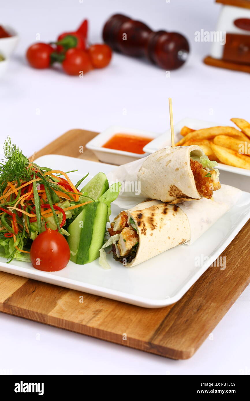 Fried chicken stuffed tortilla wrap sandwich with vegetables and french ...