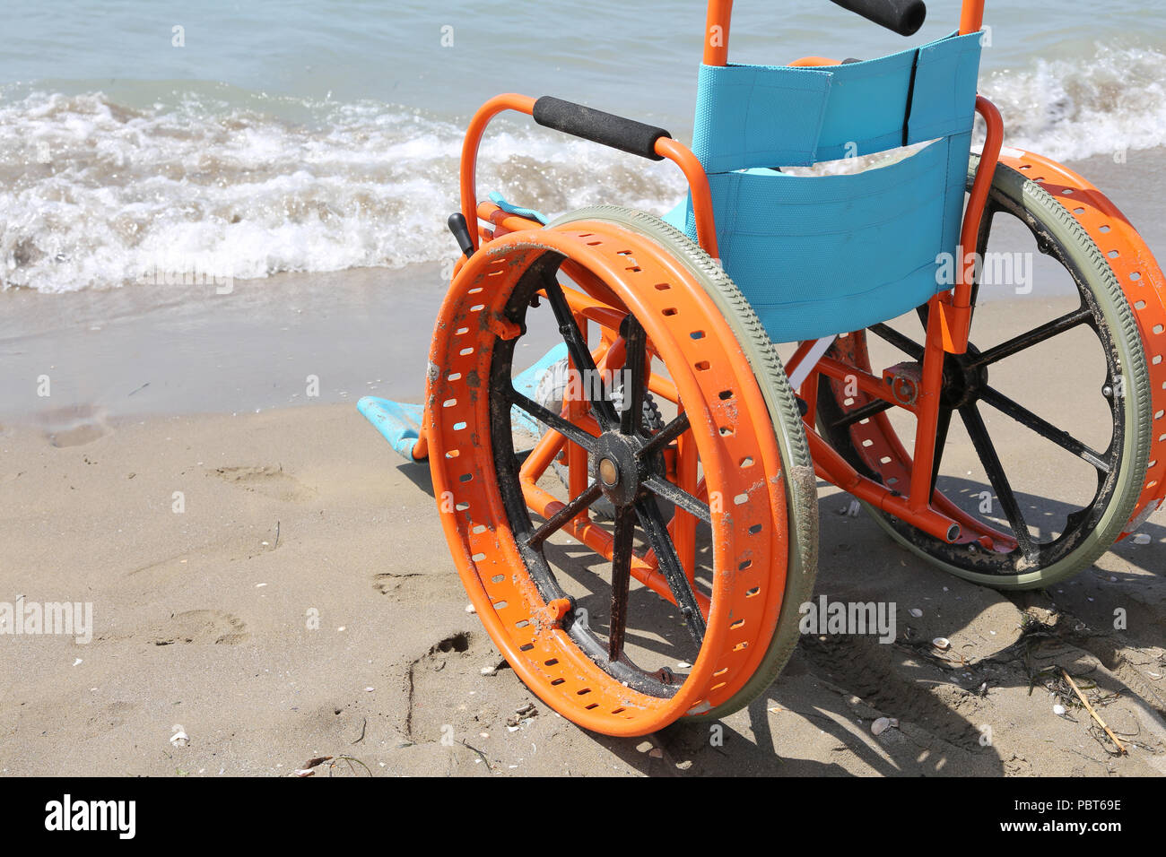 orange wheelchair used to help disabled people get to the sea Stock ...