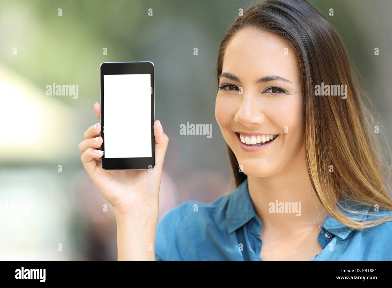 Happy lady showing a blank phone screen mock up in the street Stock ...