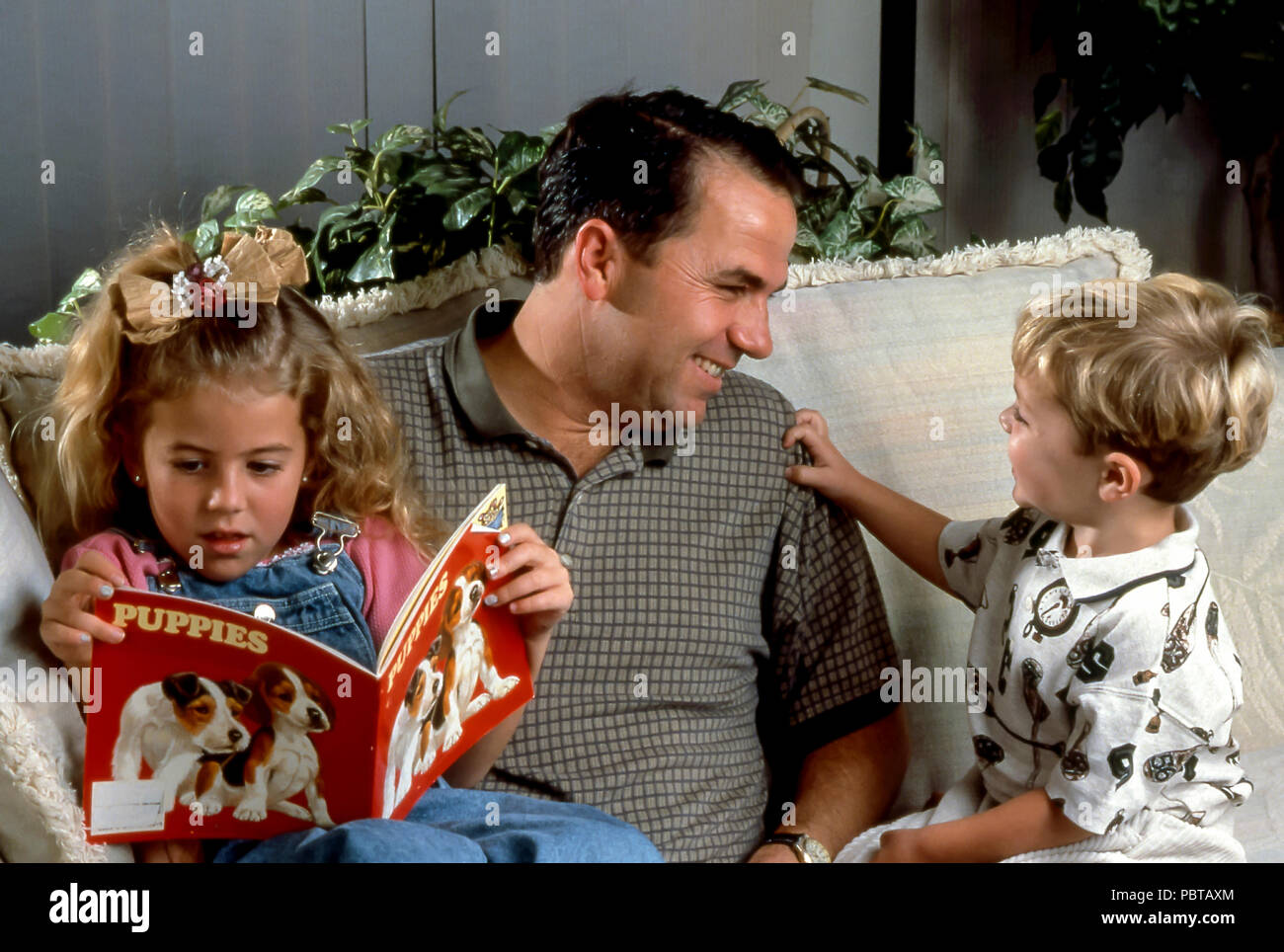 Young father interacts with his two children at home. MR © Myrleen ...