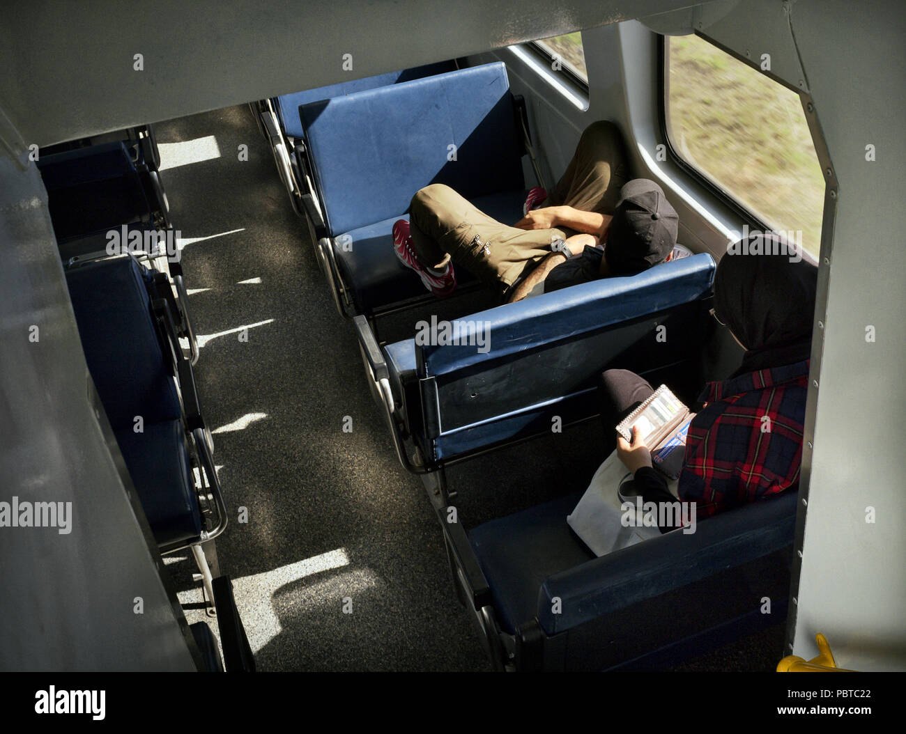 Overhead view of two seated train passengers and window Stock Photo - Alamy