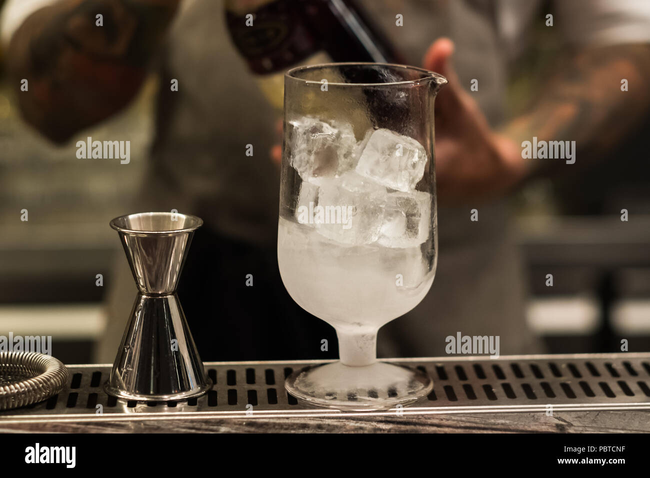 A glass with alcoholic cocktail standing on bar counter. Mixing alcohol ...