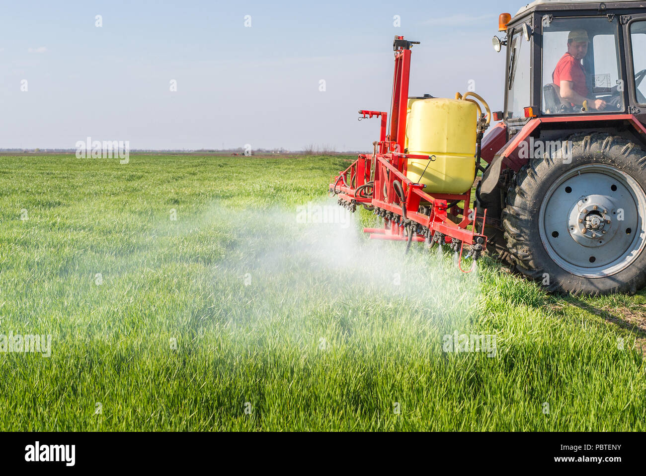 Tractor spraying wheat field with sprayer Stock Photo - Alamy
