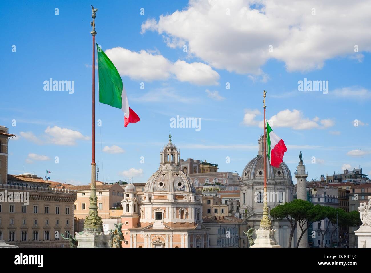 Italian flags with a glimpse of the roofs of Rome, on a summer day with ...