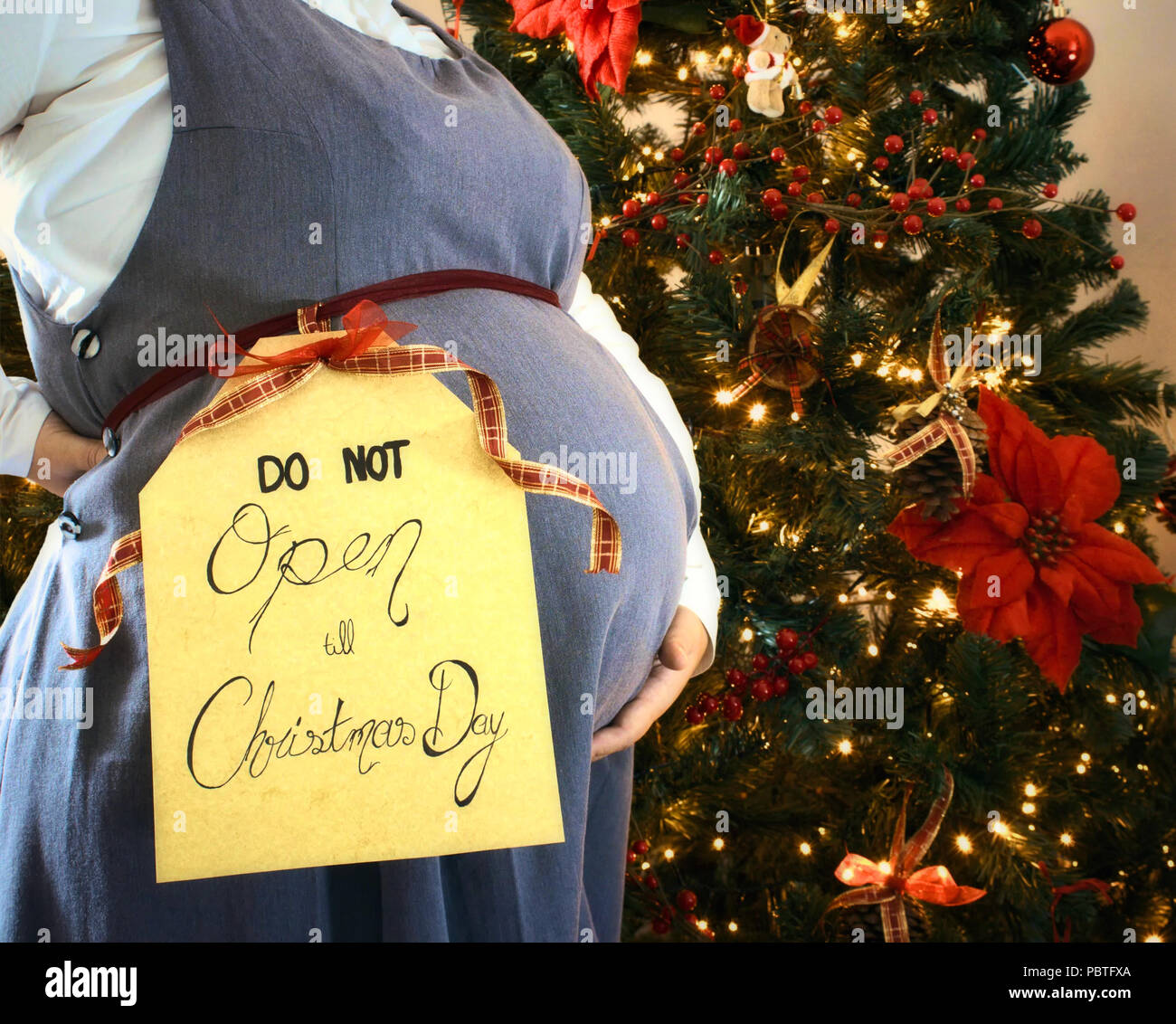 Pregnant woman showing belly with Christmas tree and "Do not open till ...