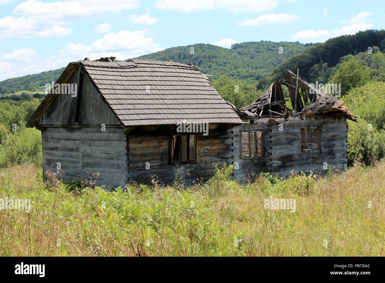 Old wooden house ruins with partially broken and fallen roof, missing windows and dilapidated ...