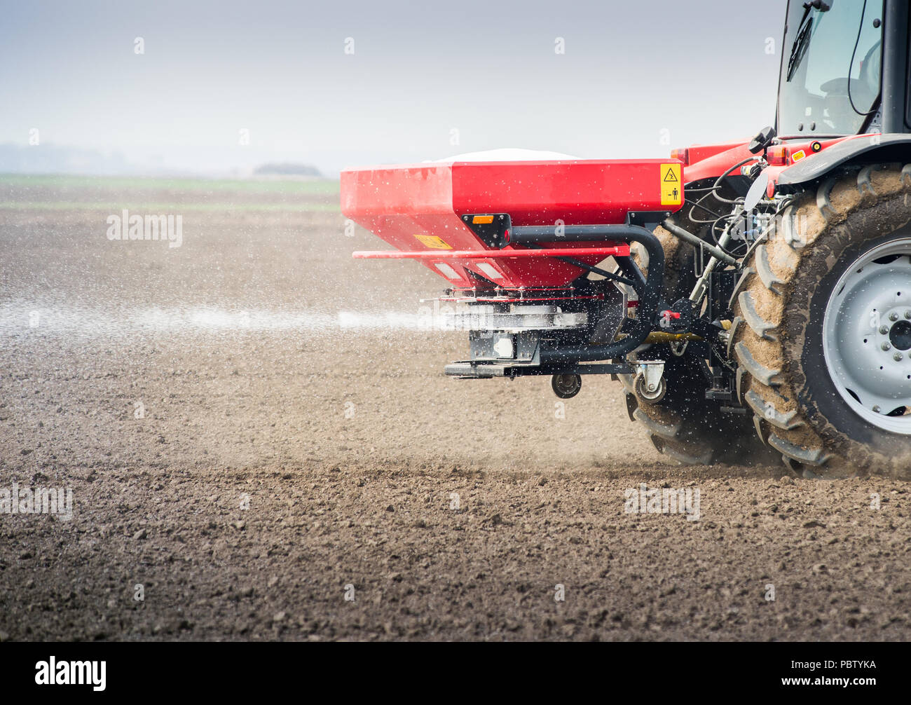 Tractor and fertilizer spreader in field Stock Photo - Alamy