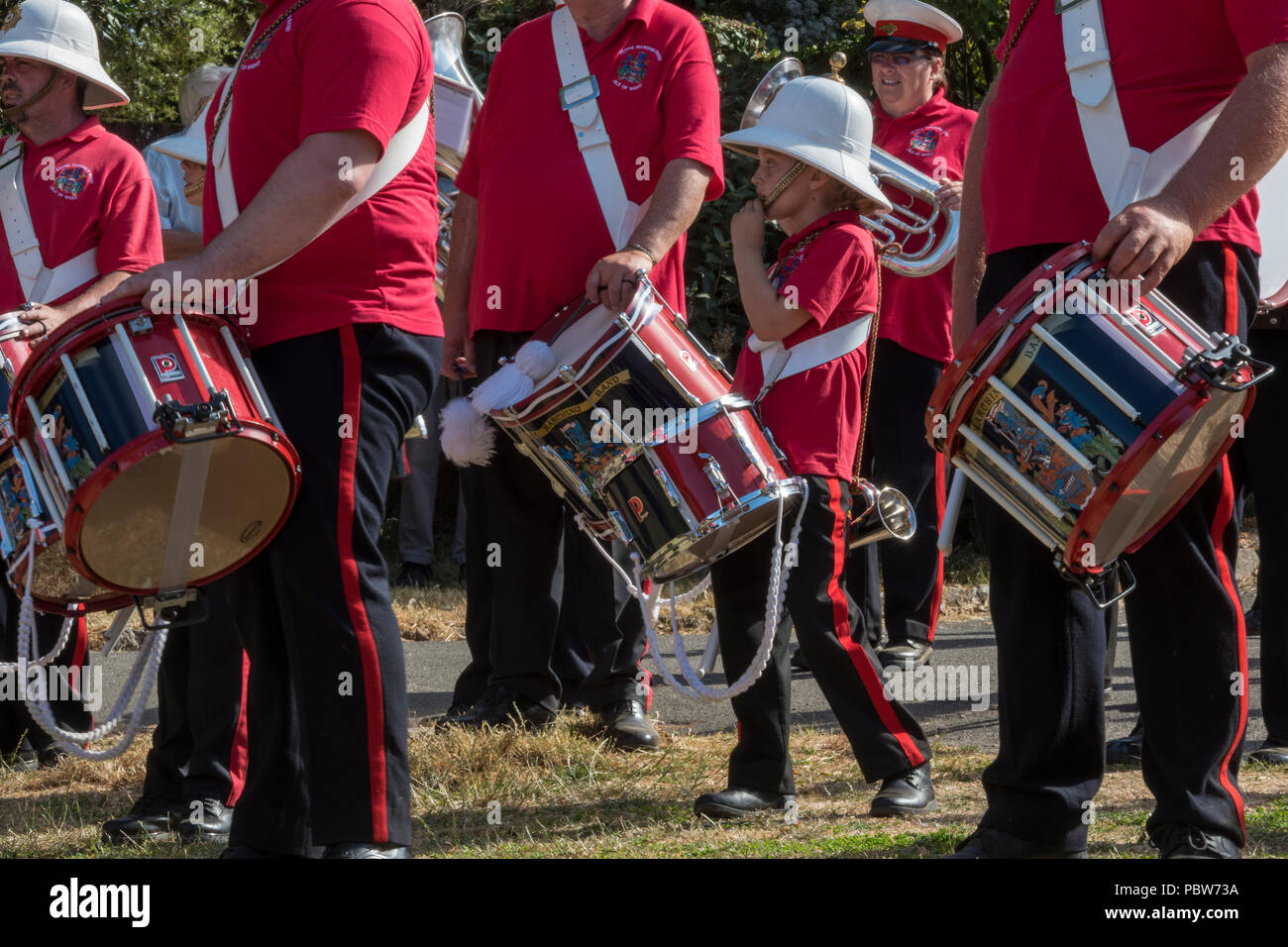 a small boy playing a drum in a marching band surrounded by taller men ...