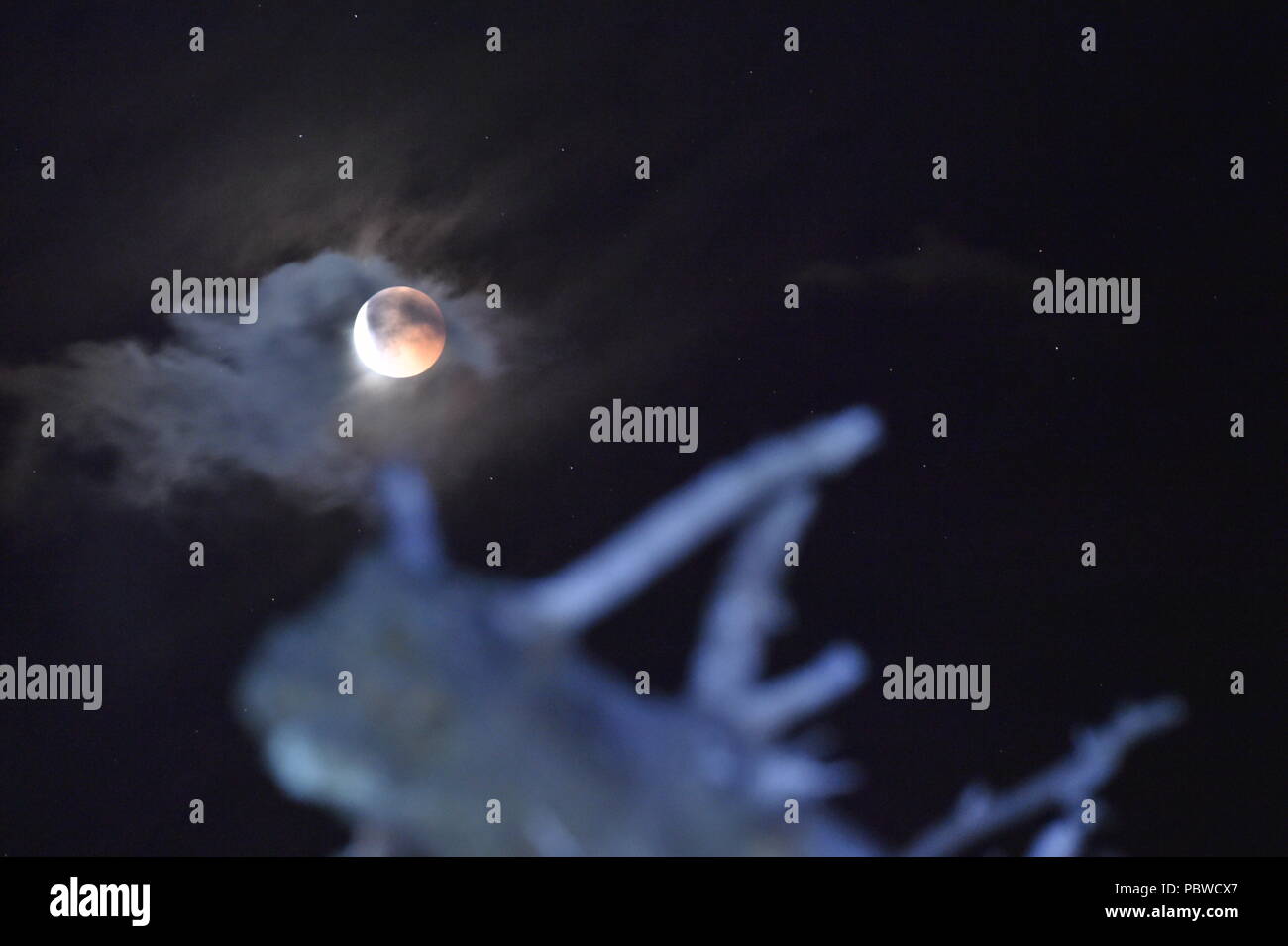 Plechy, Czech Republic. 27th July, 2018. The Moon is partly covered ...