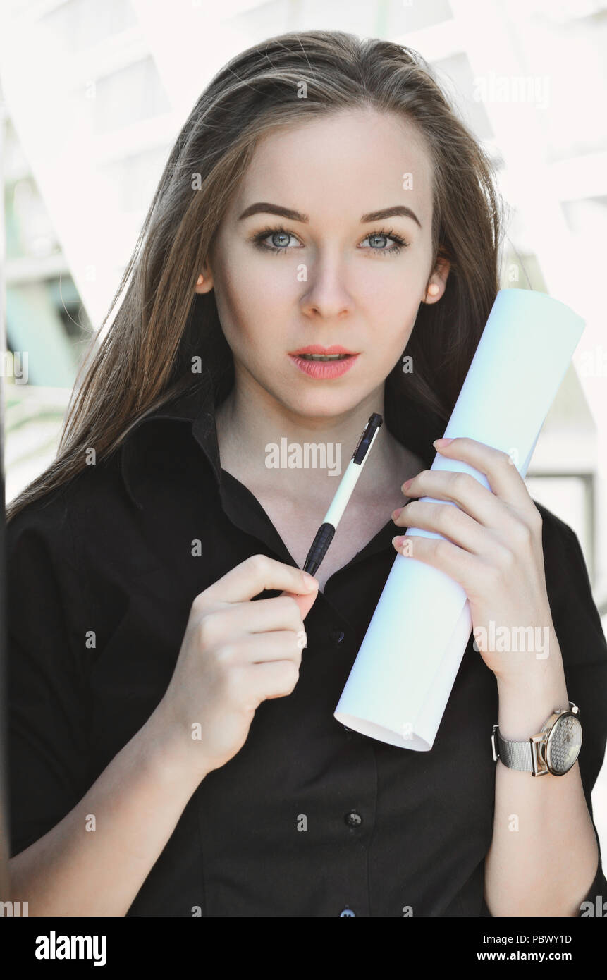 Portrait of business lady in black shirt with pen and paper, looking at ...